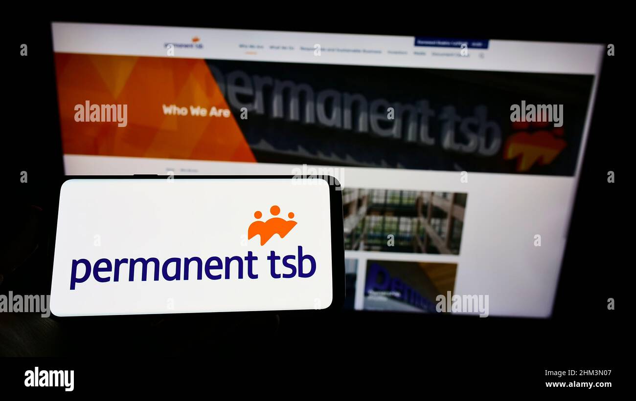Person holding cellphone with logo of Irish company Permanent TSB Group ...