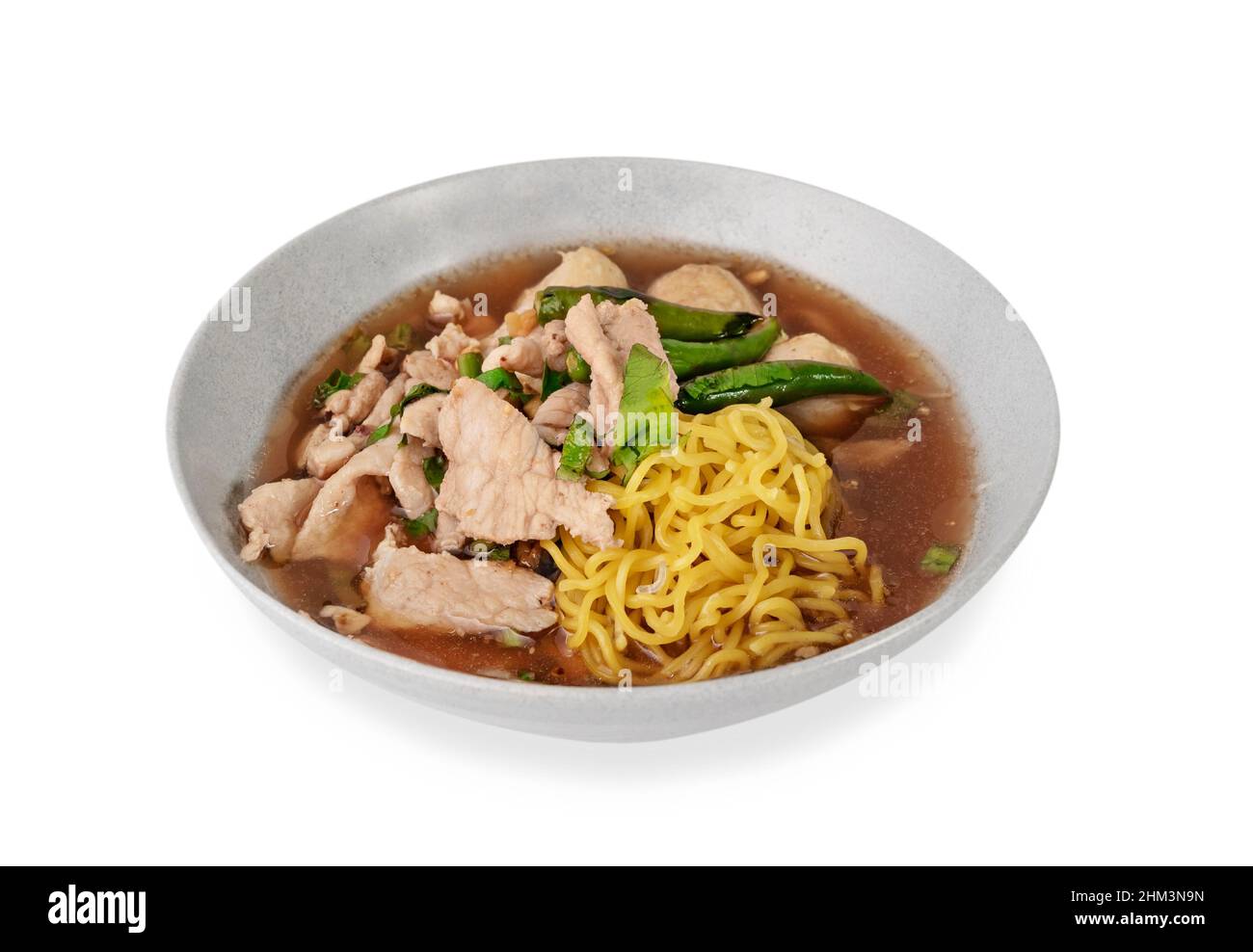 Asian yellow noodles with pork and vegetables in bowl over white ...