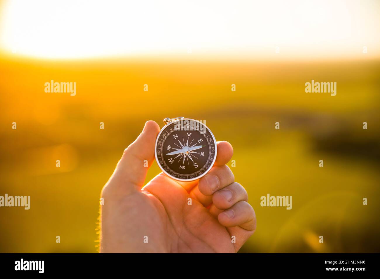 a hand holding a compass in a natural landscape at sunset Stock Photo ...