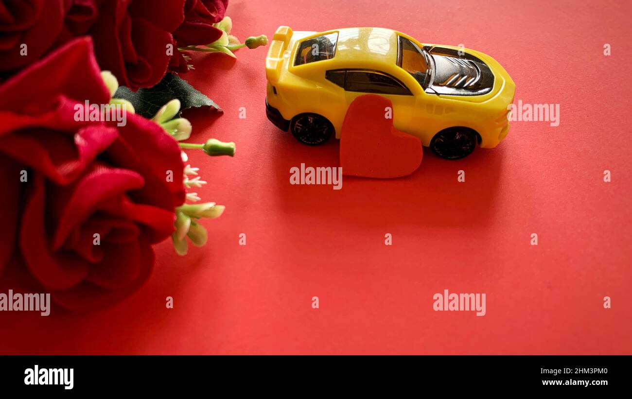 Top view of red roses, yellow car and heart shape with red cover ...