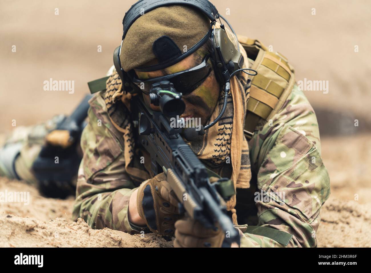 Focused soldier at ground level stance aiming using target scoop . High ...