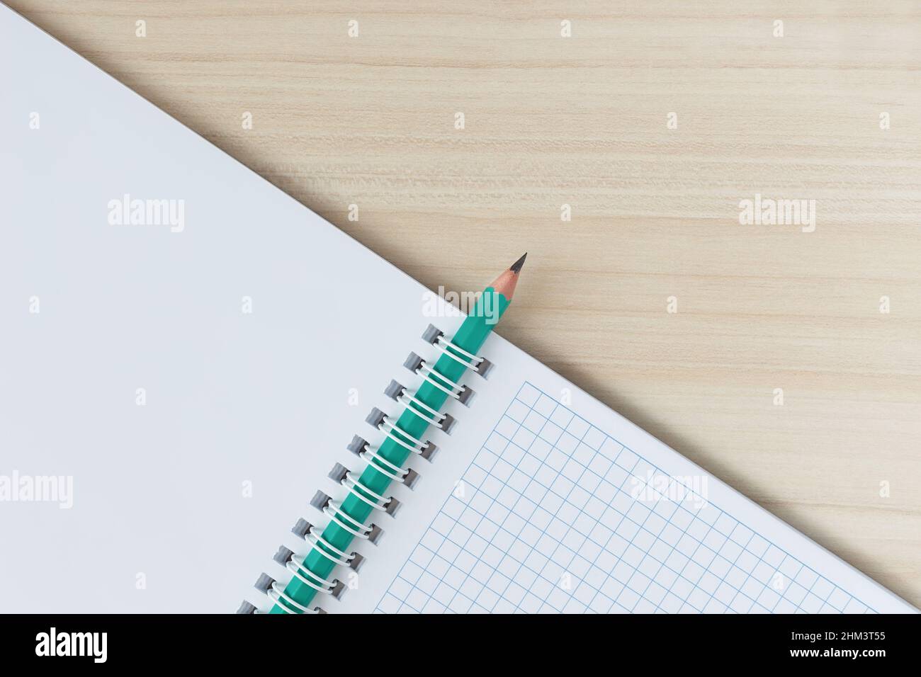 A pencil inserted into a spiral clip of a notepad, on a wooden table ...