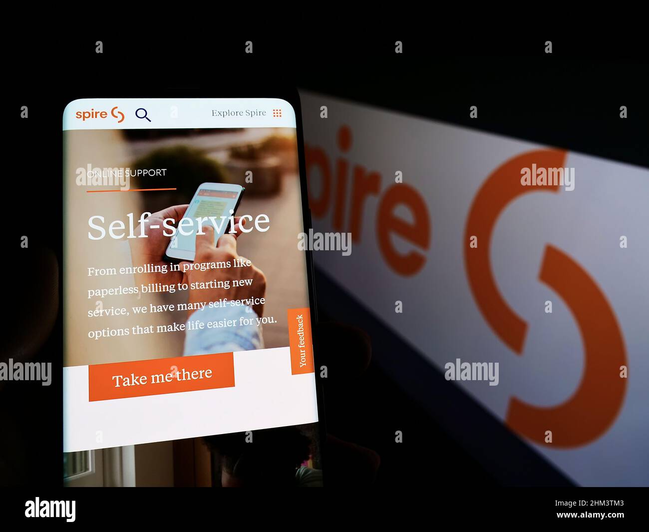 Person holding cellphone with website of US utility company Spire Inc ...