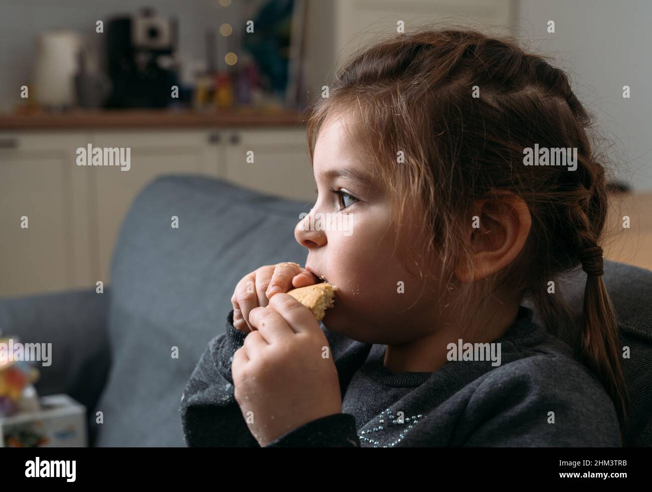 Pretty caucasian girl eating cookies at home on the sofa Stock Photo ...