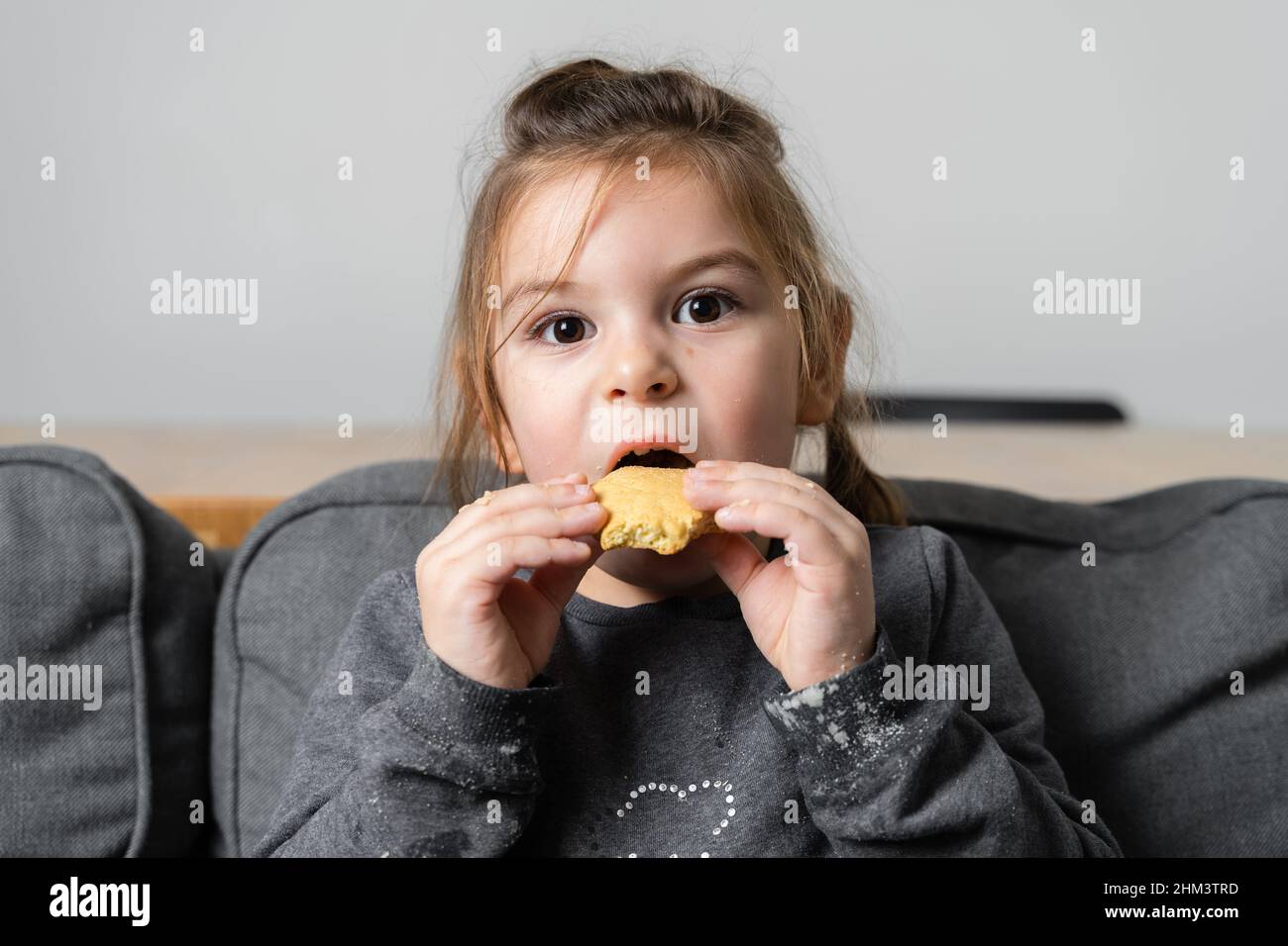 Pretty caucasian girl eating cookies at home on the sofa Stock Photo ...