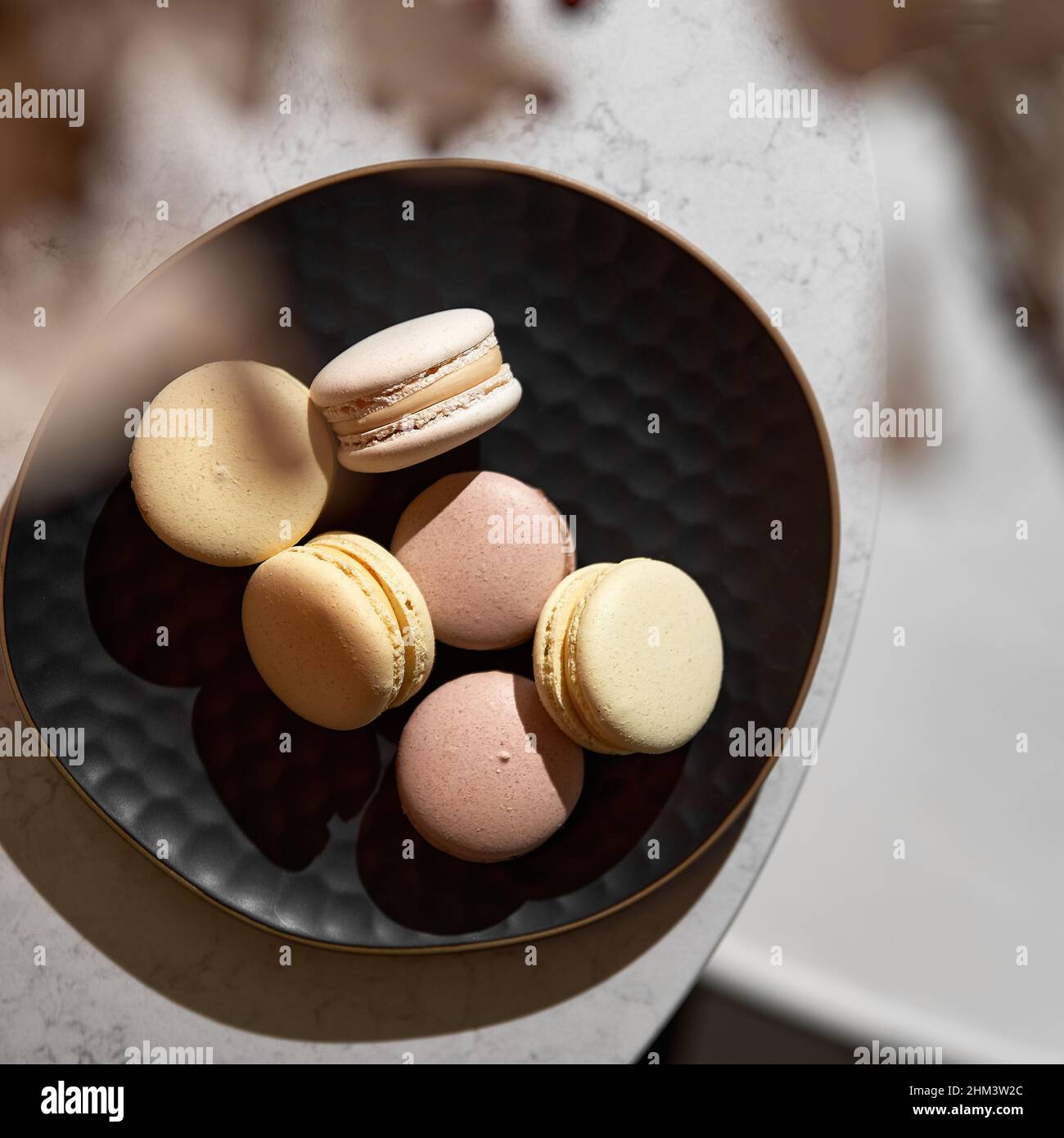 Colorful French or Italian macarons stack on white plate put on wood ...