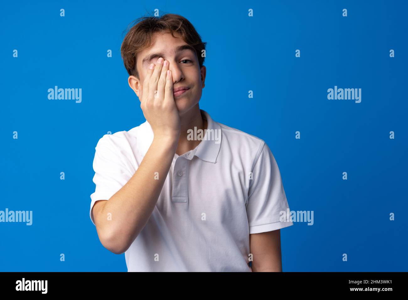 Sad teenager boy failed, touching face against blue background Stock ...