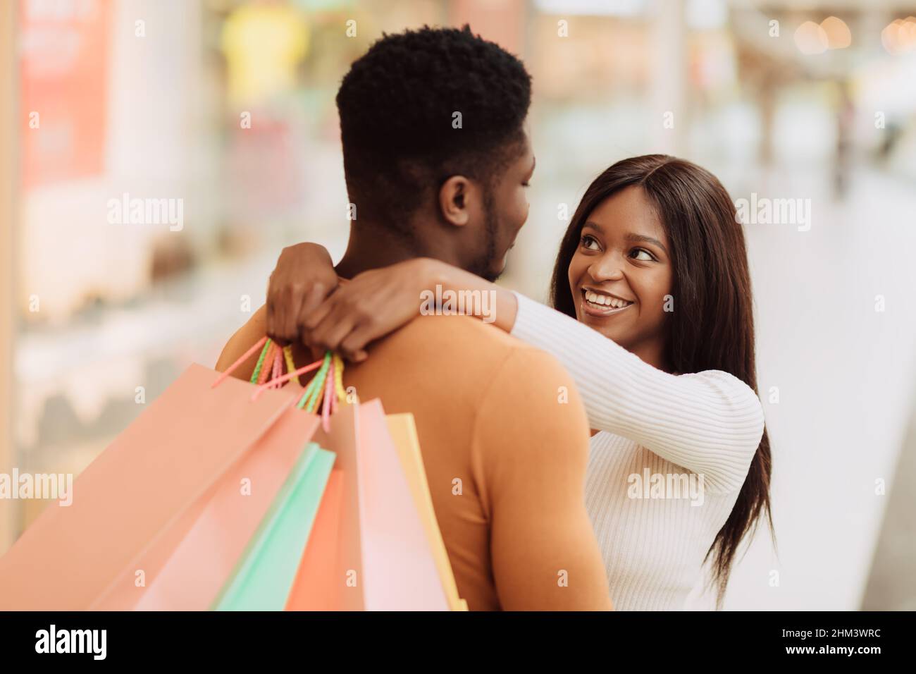 Happy black couple hugging and holding shopping bags Stock Photo - Alamy