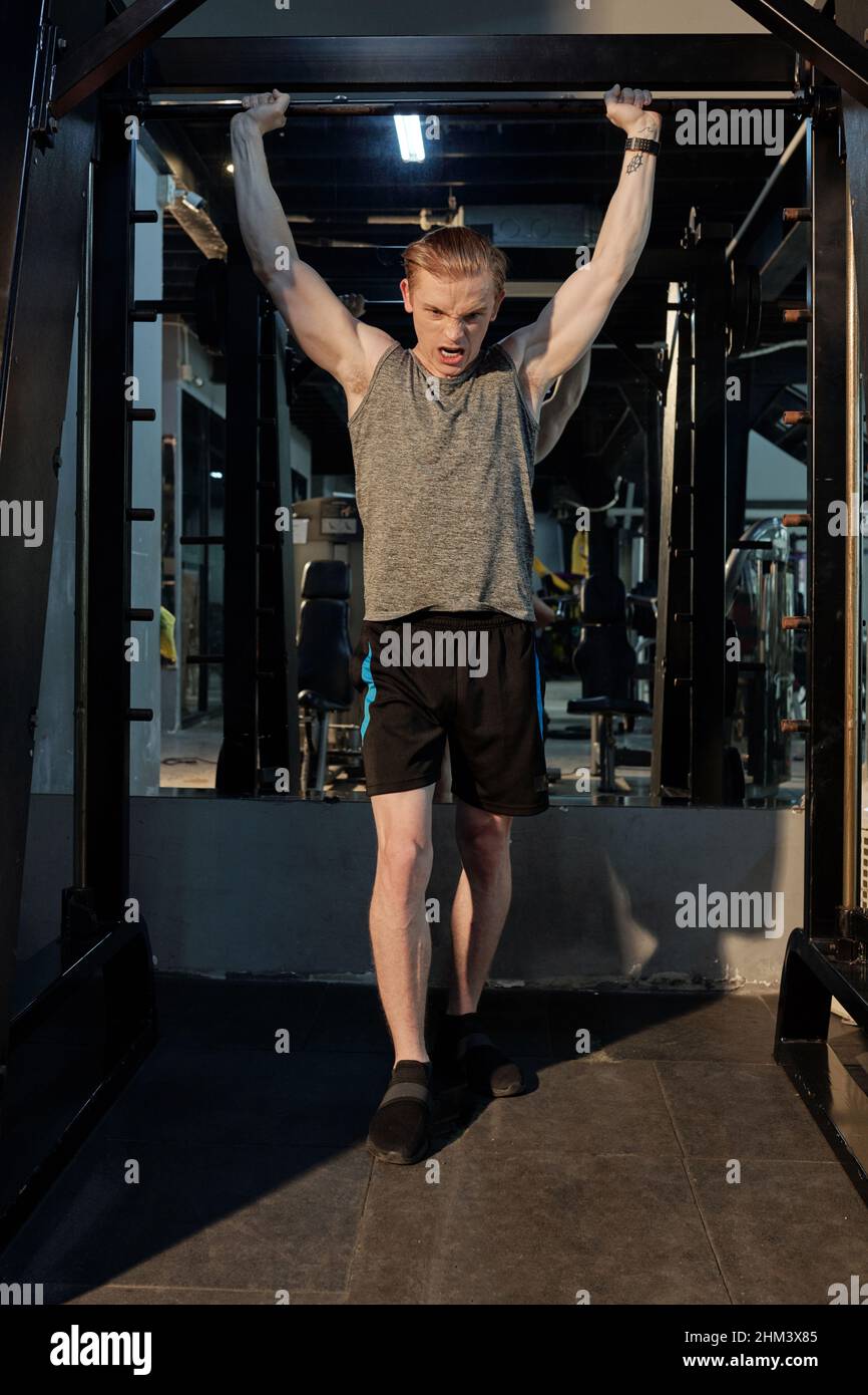 Emotional strong athlete shouting when lifting heavy weights in gym ...