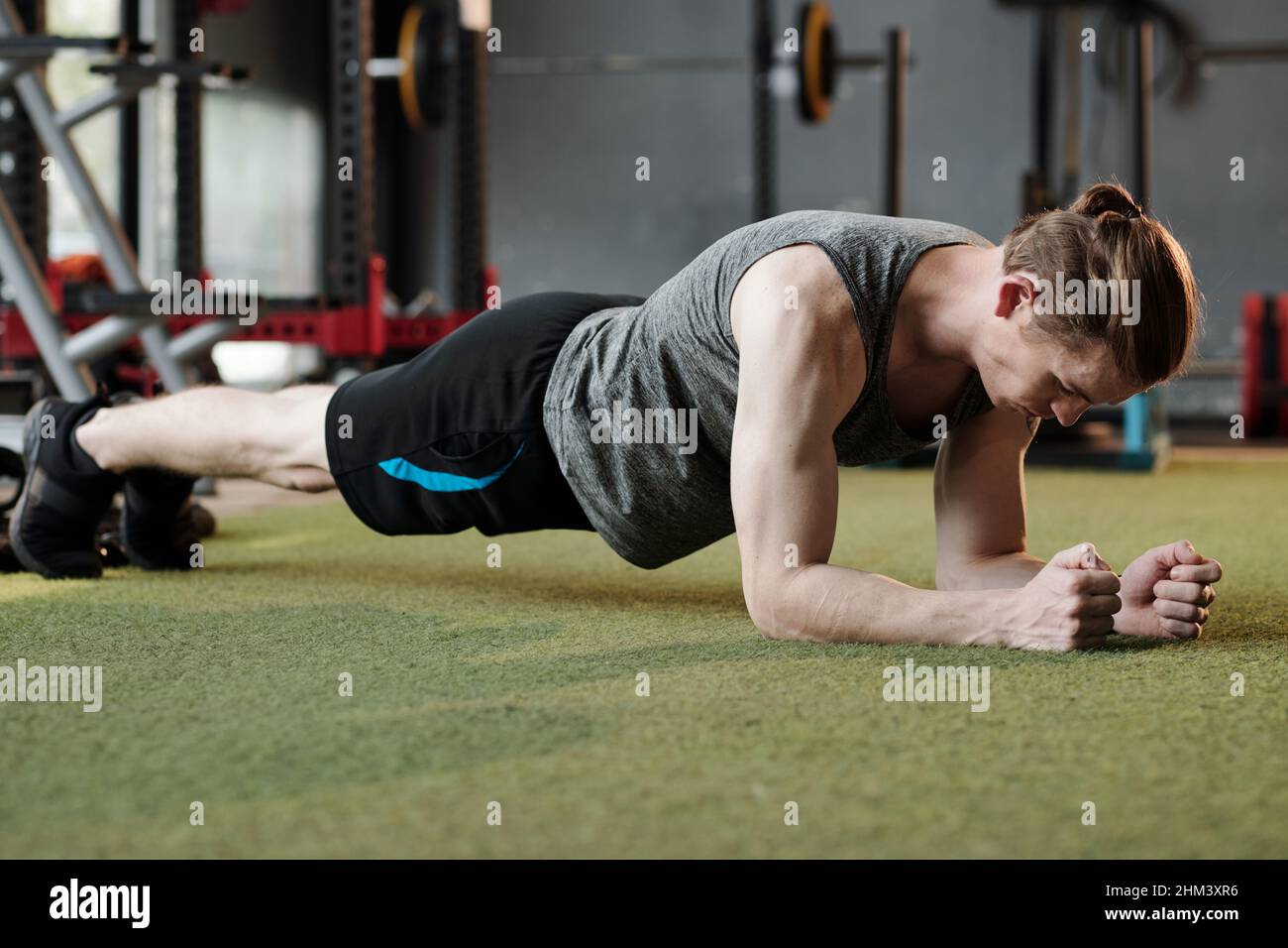 Fit strong man trying to stand in plank position as lond as possible ...