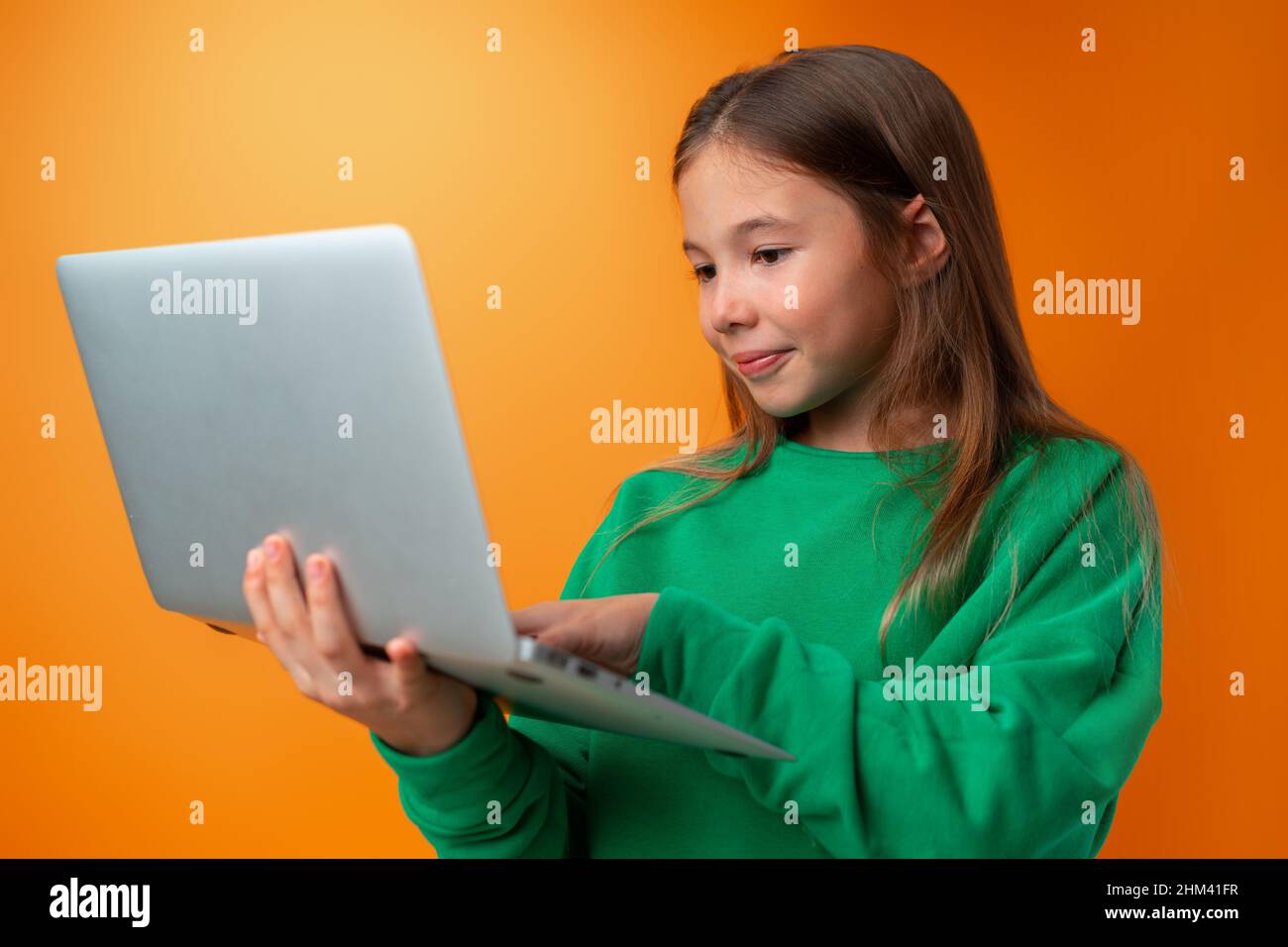 Portrait of a cheerful young teen girl holding laptop computer against ...