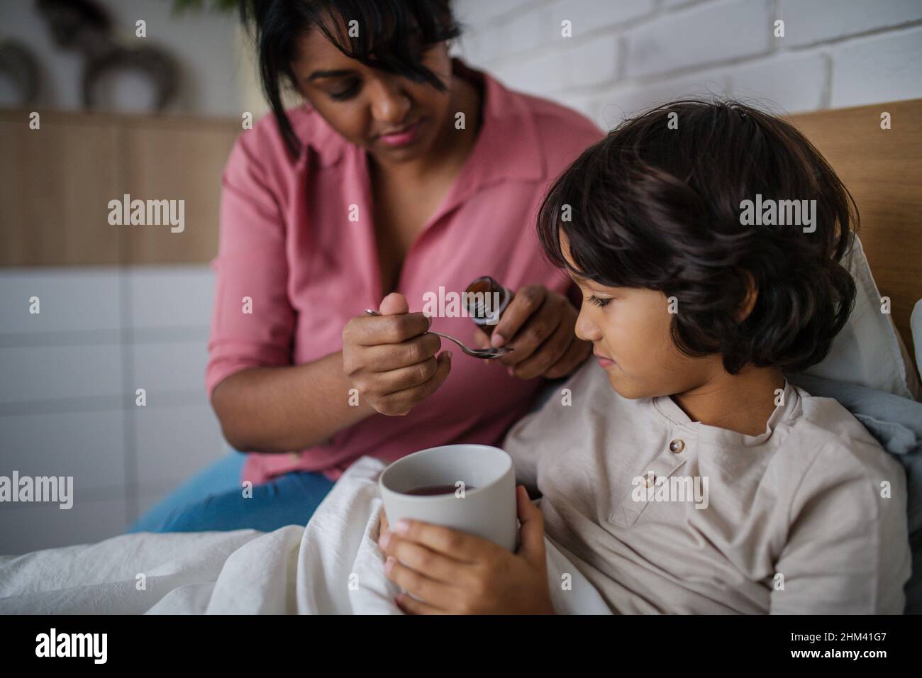 Ill boy taking medicine from his mother at home Stock Photo - Alamy