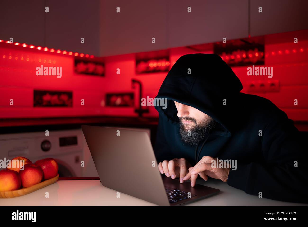 a hacker in a black hoodie with a hood on his head is sitting at a ...