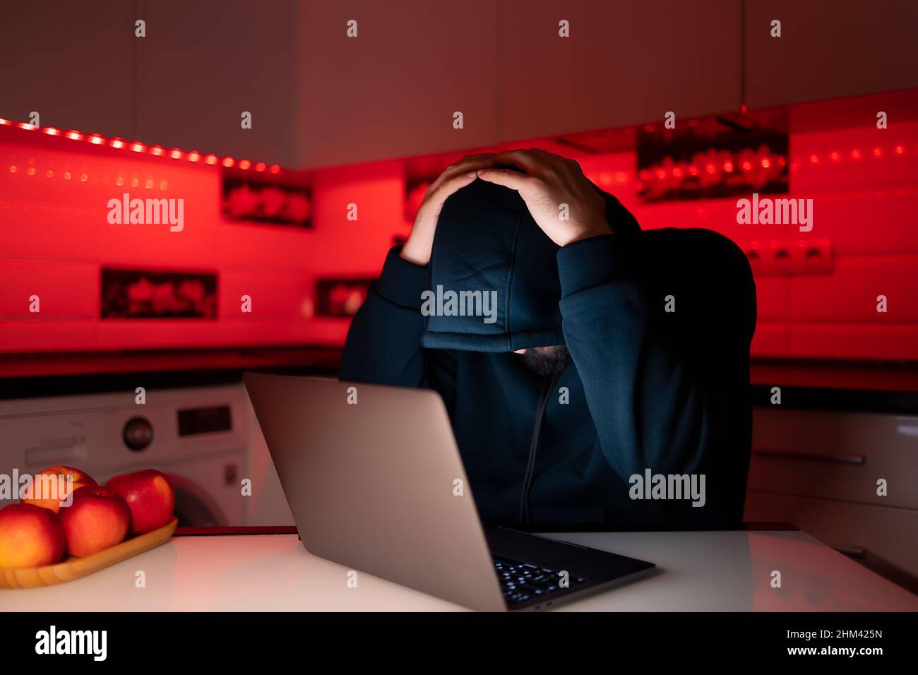 a hacker in a black hoodie with a hood on his head is sitting at a ...