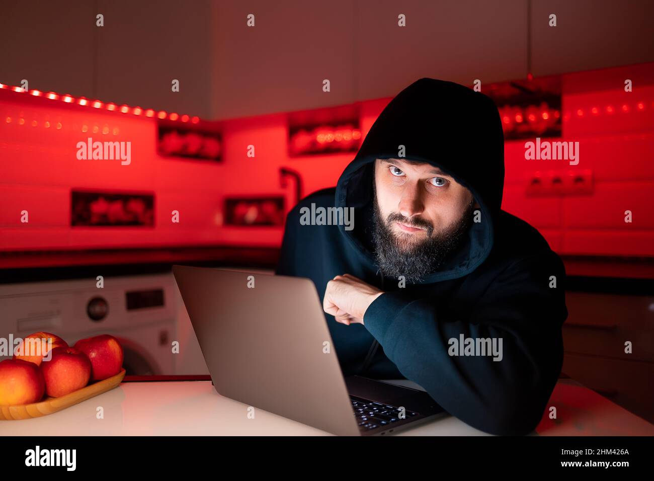 a hacker in a black hoodie with a hood on his head is sitting at a ...