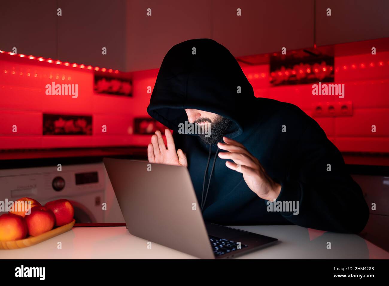 a hacker in a black hoodie with a hood on his head is sitting at a ...