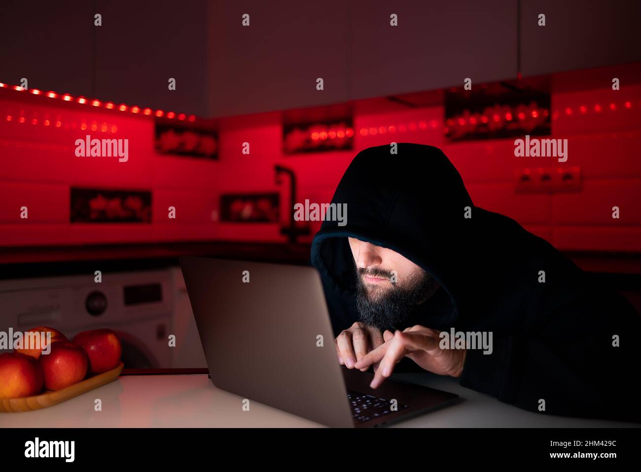 a hacker in a black hoodie with a hood on his head is sitting at a ...