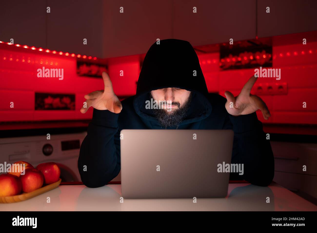 a hacker in a black hoodie with a hood on his head is sitting at a ...