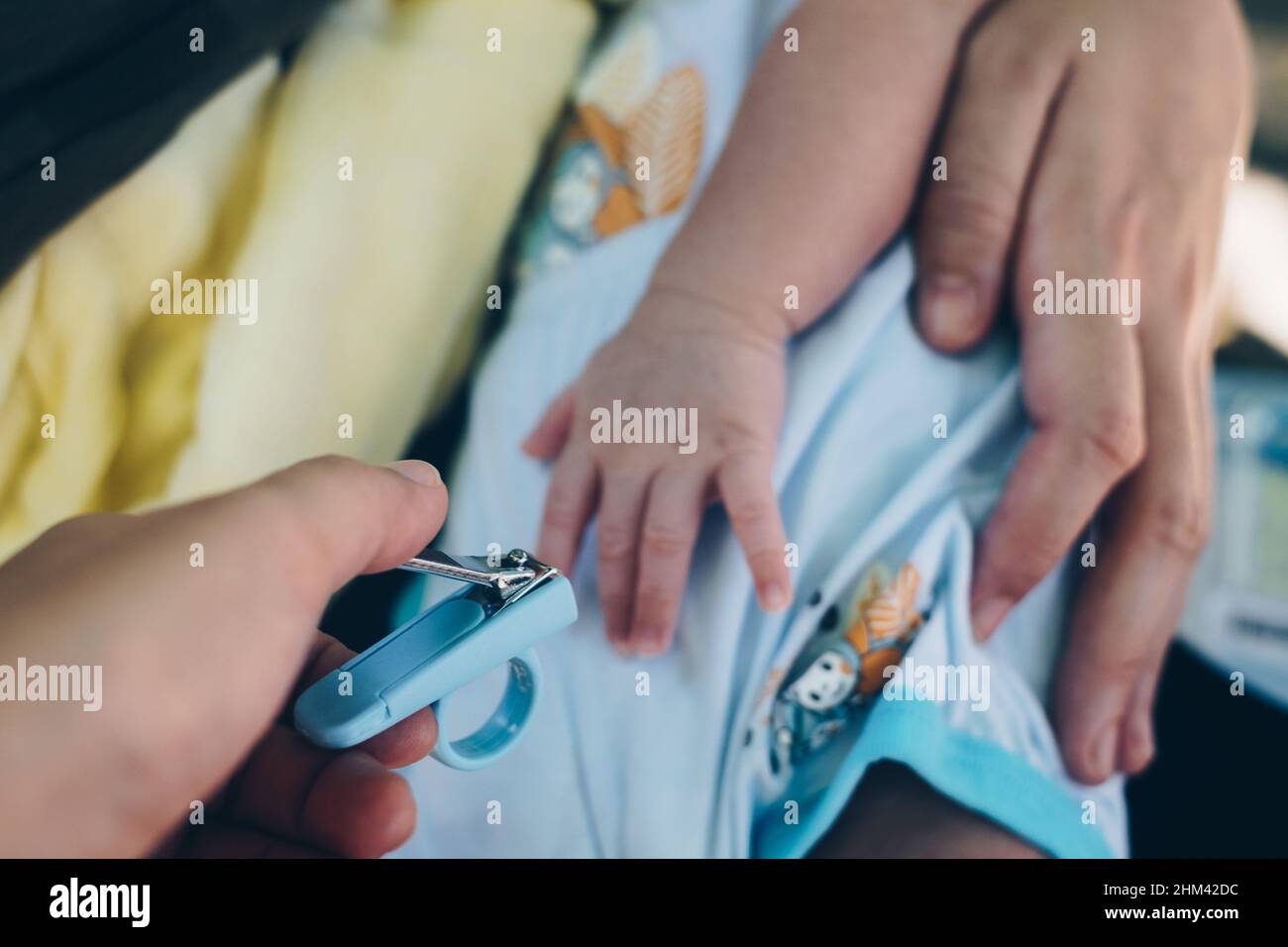 Hand holding a blue clipper to trim the baby's long fingernails for ...