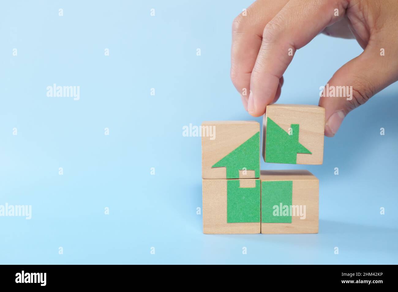 Human hand putting together house icon puzzle made of wooden blocks ...