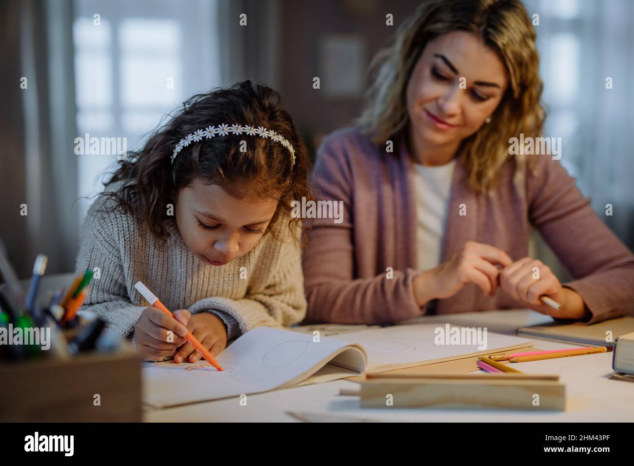 Little girl doing homework with her mother in evening at home Stock ...