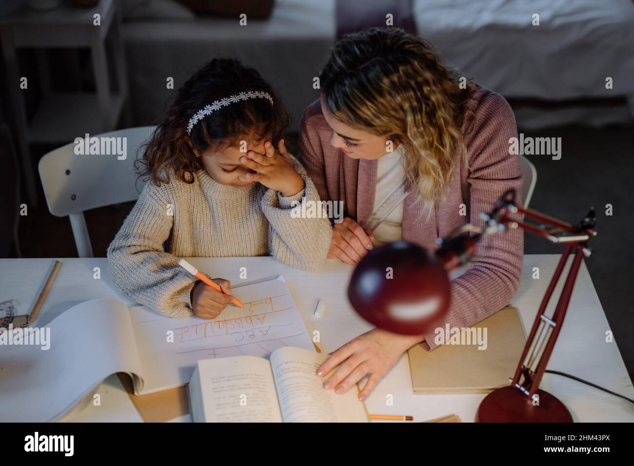 High angle view of little girl doing homework with her mother in ...
