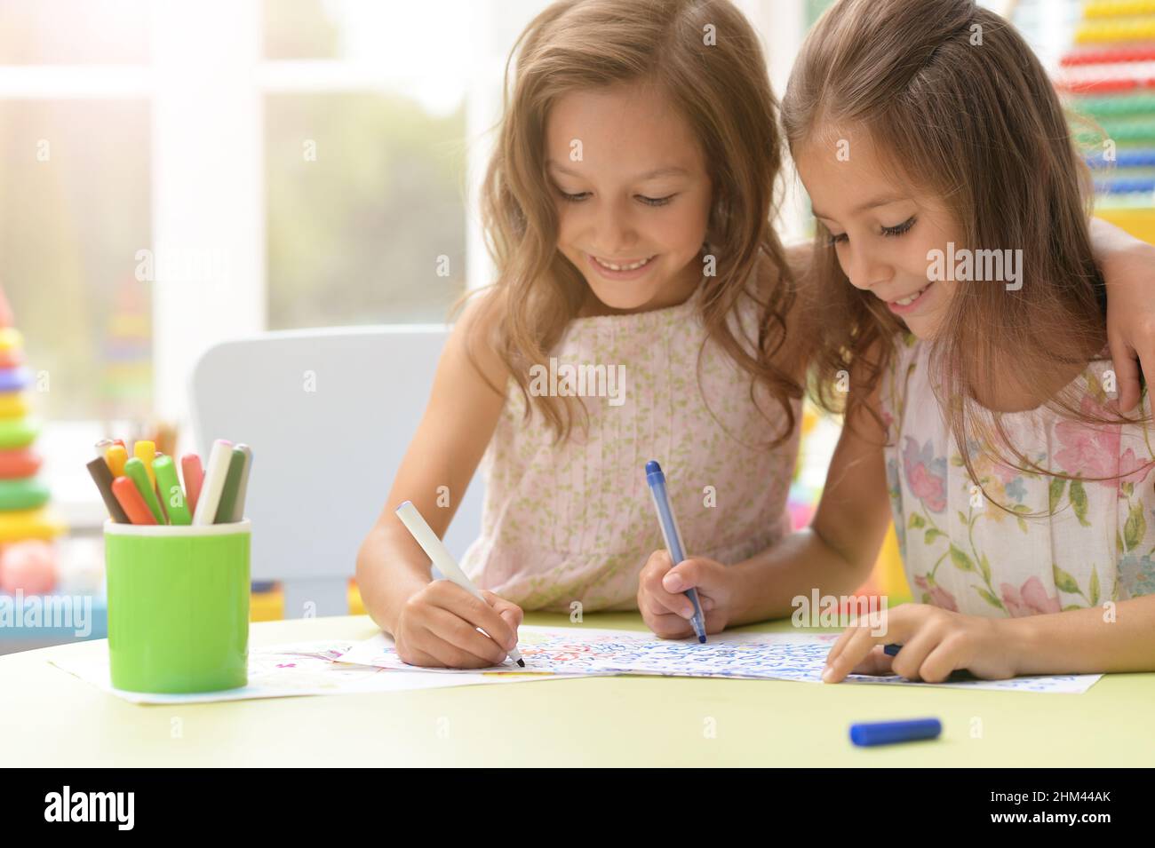 Two cute little girls drawing with pencils Stock Photo - Alamy