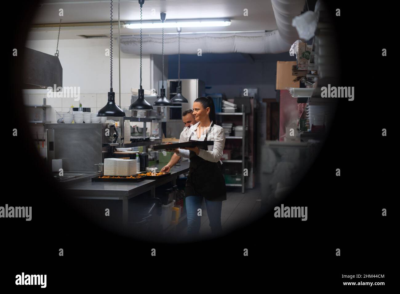 Happy chef and cook working on their dishes in restaurant kitchen, shot ...
