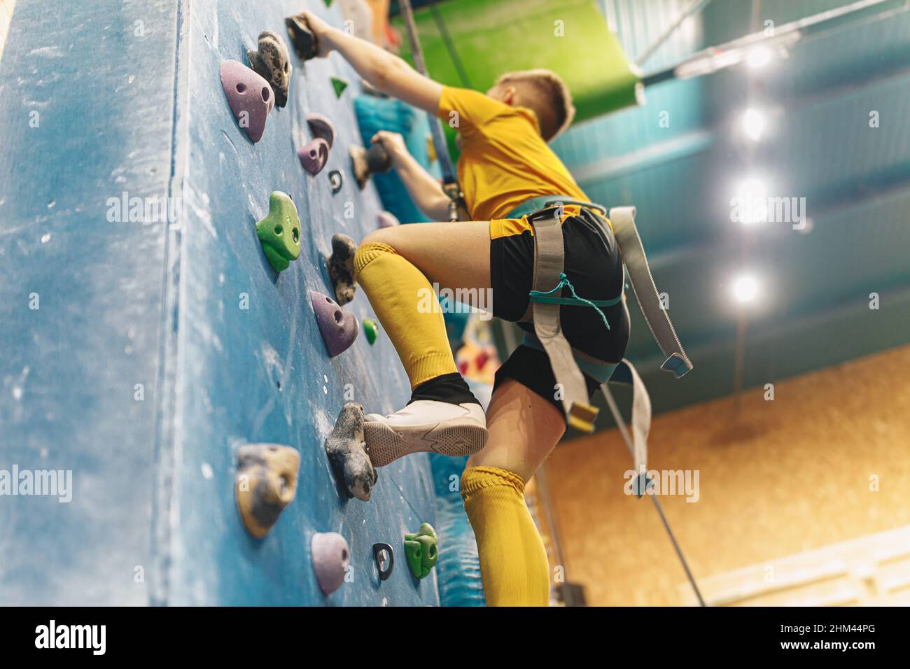 Teenage boy at indoor climbing wall. Kid having fun at bouldering wall ...