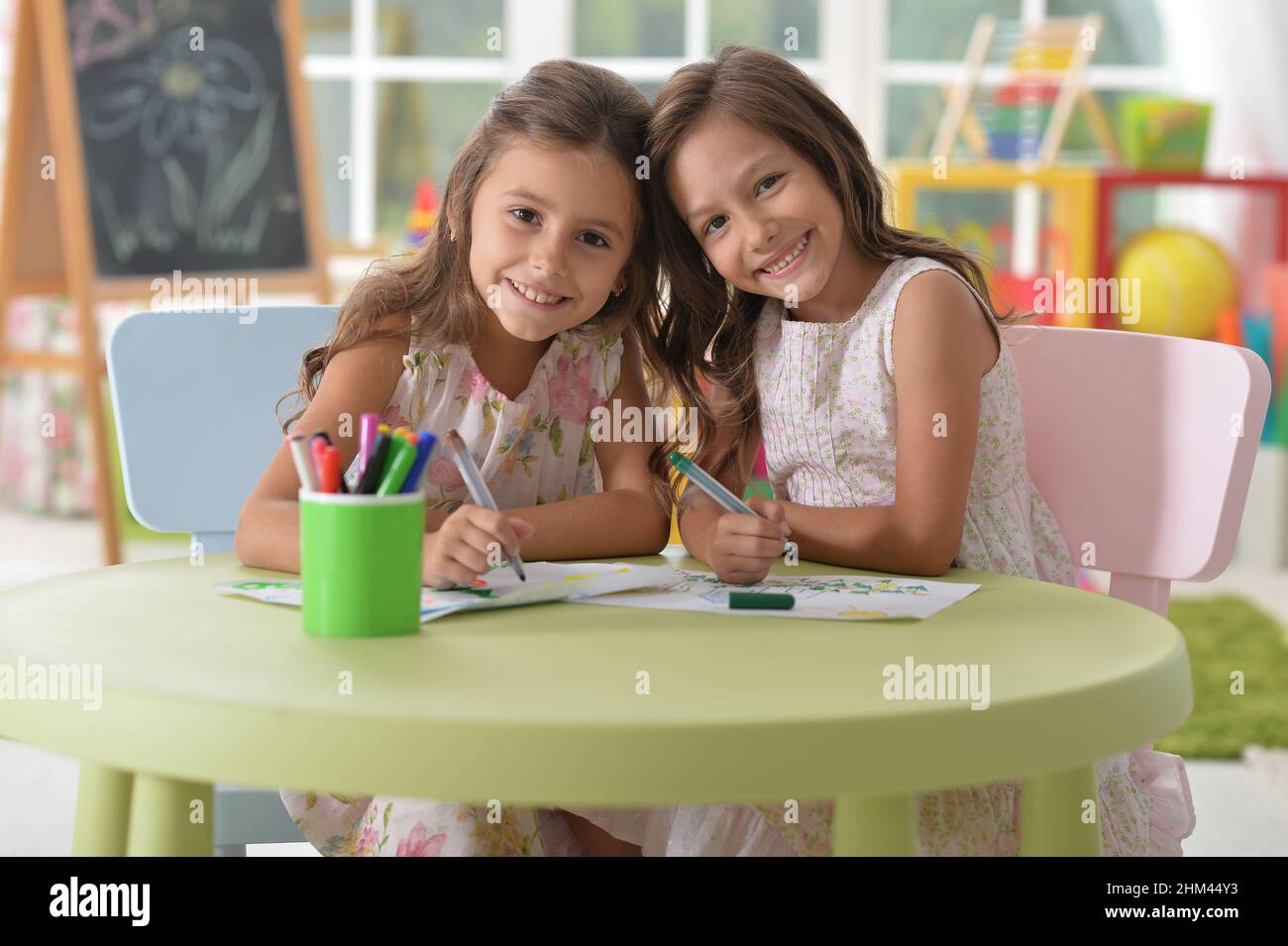 Two cute little girls drawing with pencils Stock Photo - Alamy
