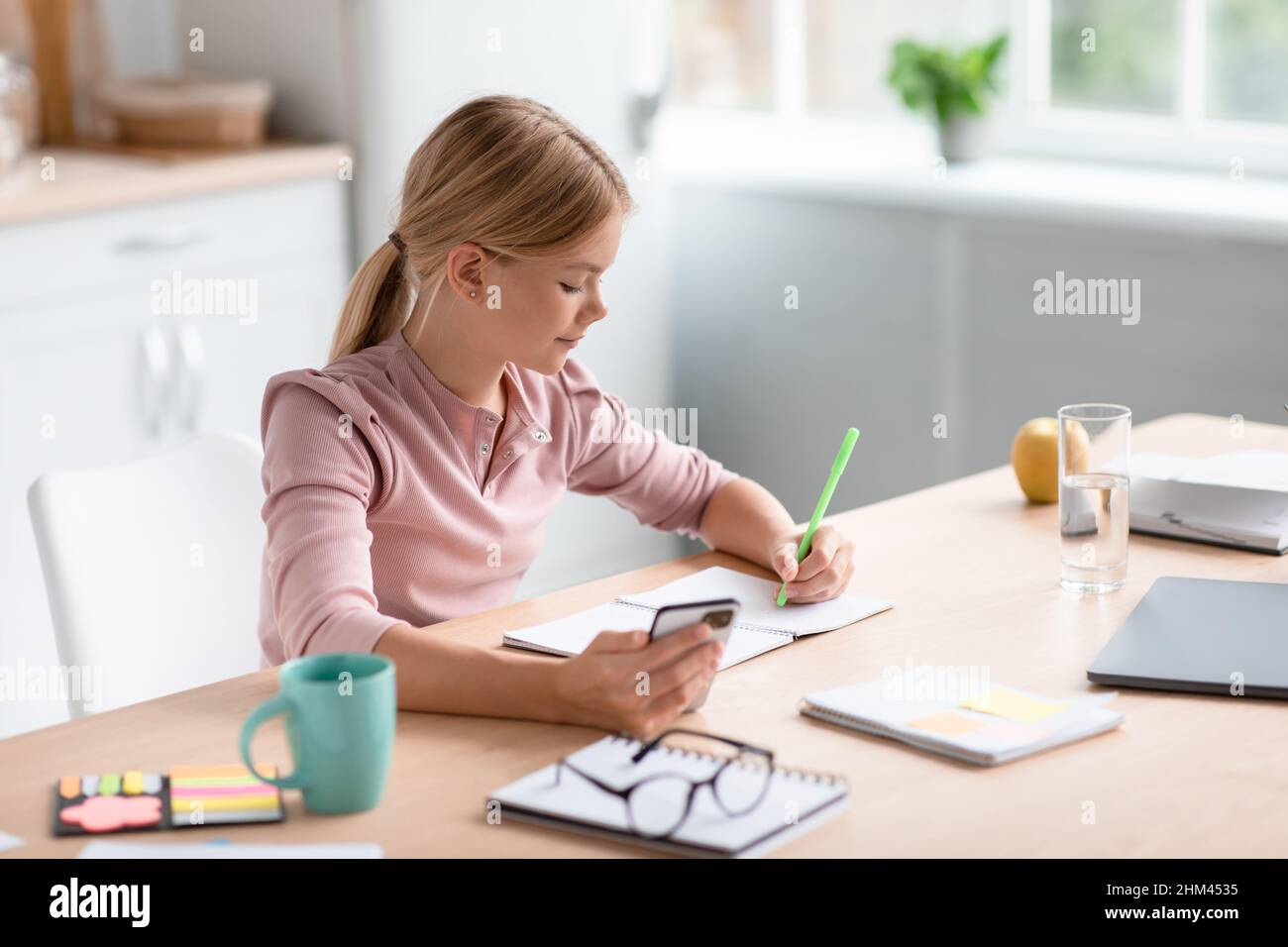 Serious busy pretty caucasian teenage girl blonde makes notes with ...
