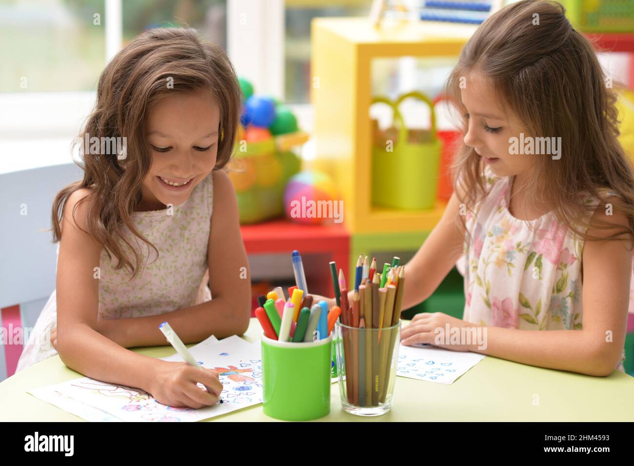 Two cute little girls drawing with pencils Stock Photo - Alamy