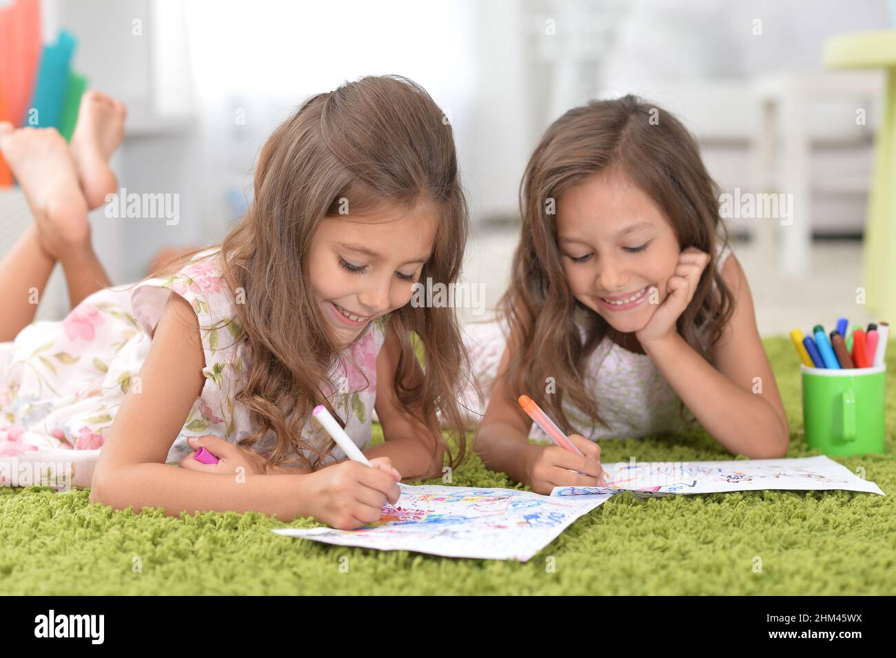 Two cute little girls drawing with pencils Stock Photo - Alamy