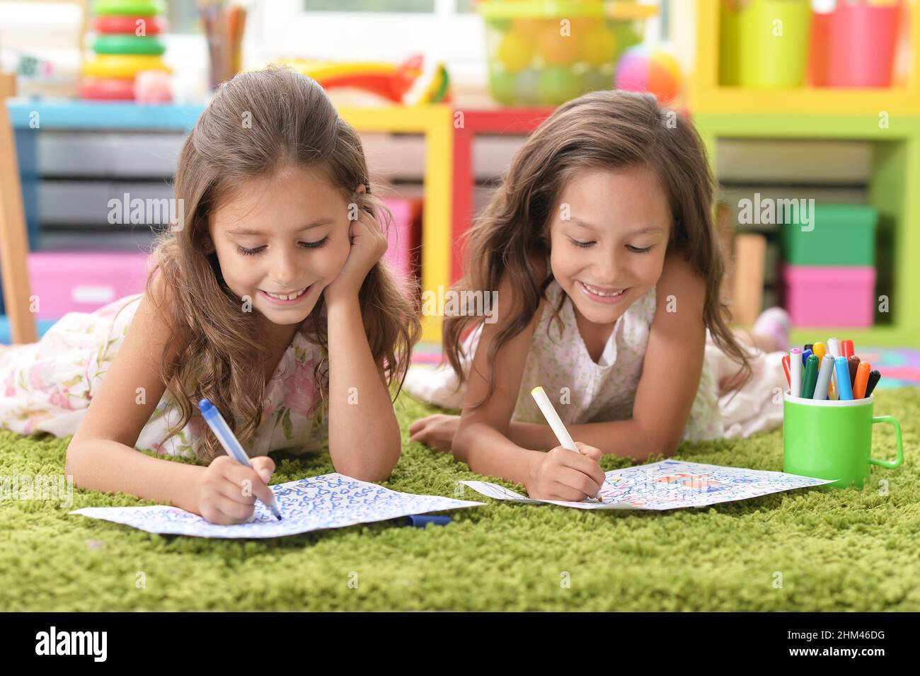 Two cute little girls drawing with pencils Stock Photo - Alamy