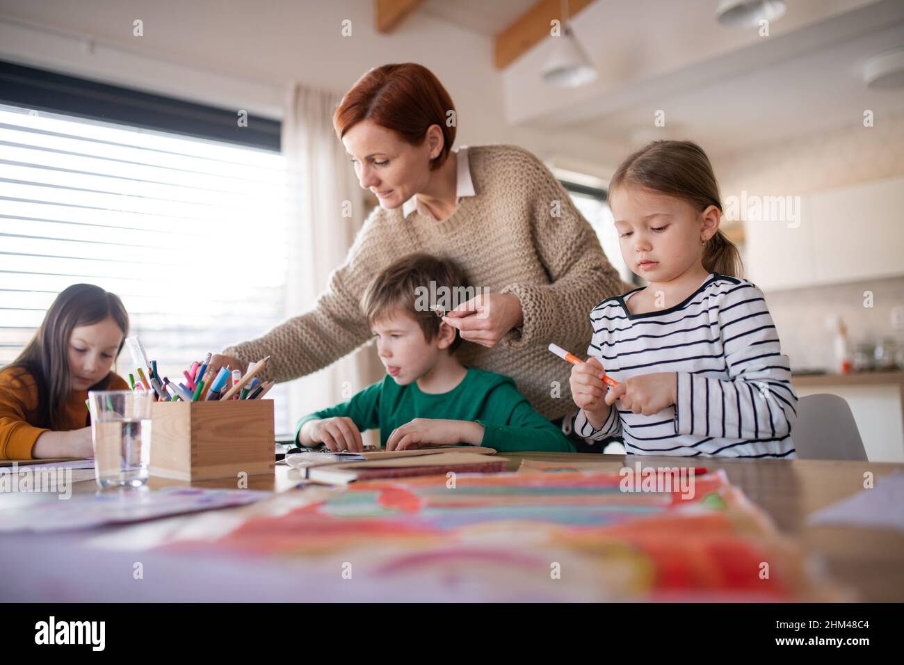 Mother of three little children supervising them when diong homework at ...