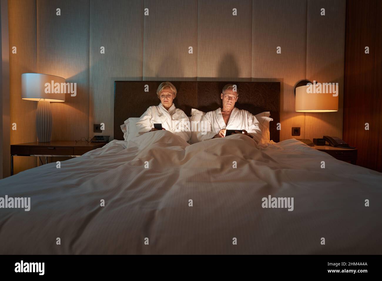 Couple of people using electronic devices before going to sleep Stock ...