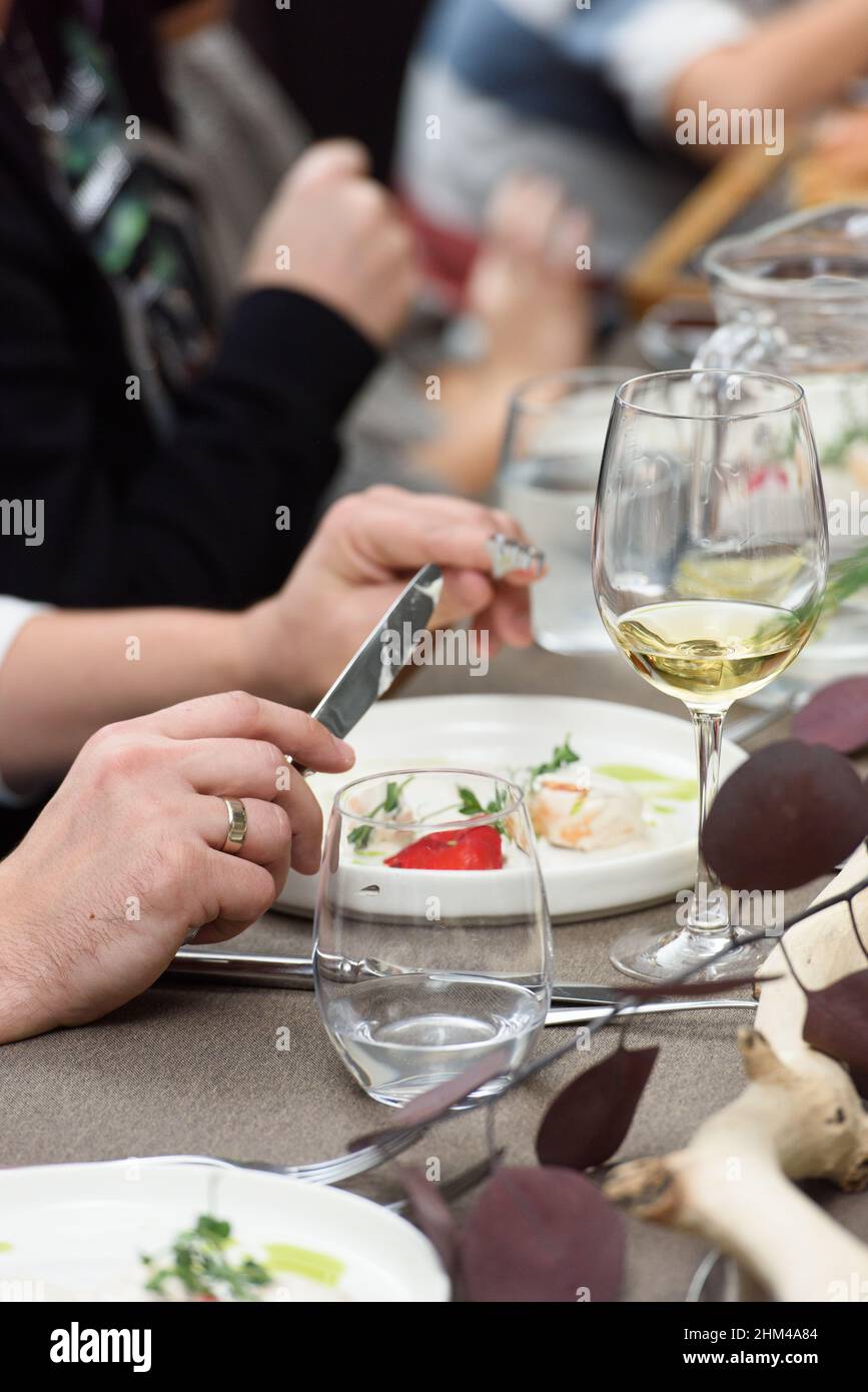 Man eats a dish of fish balls in a creamy sauce served on a table in a ...