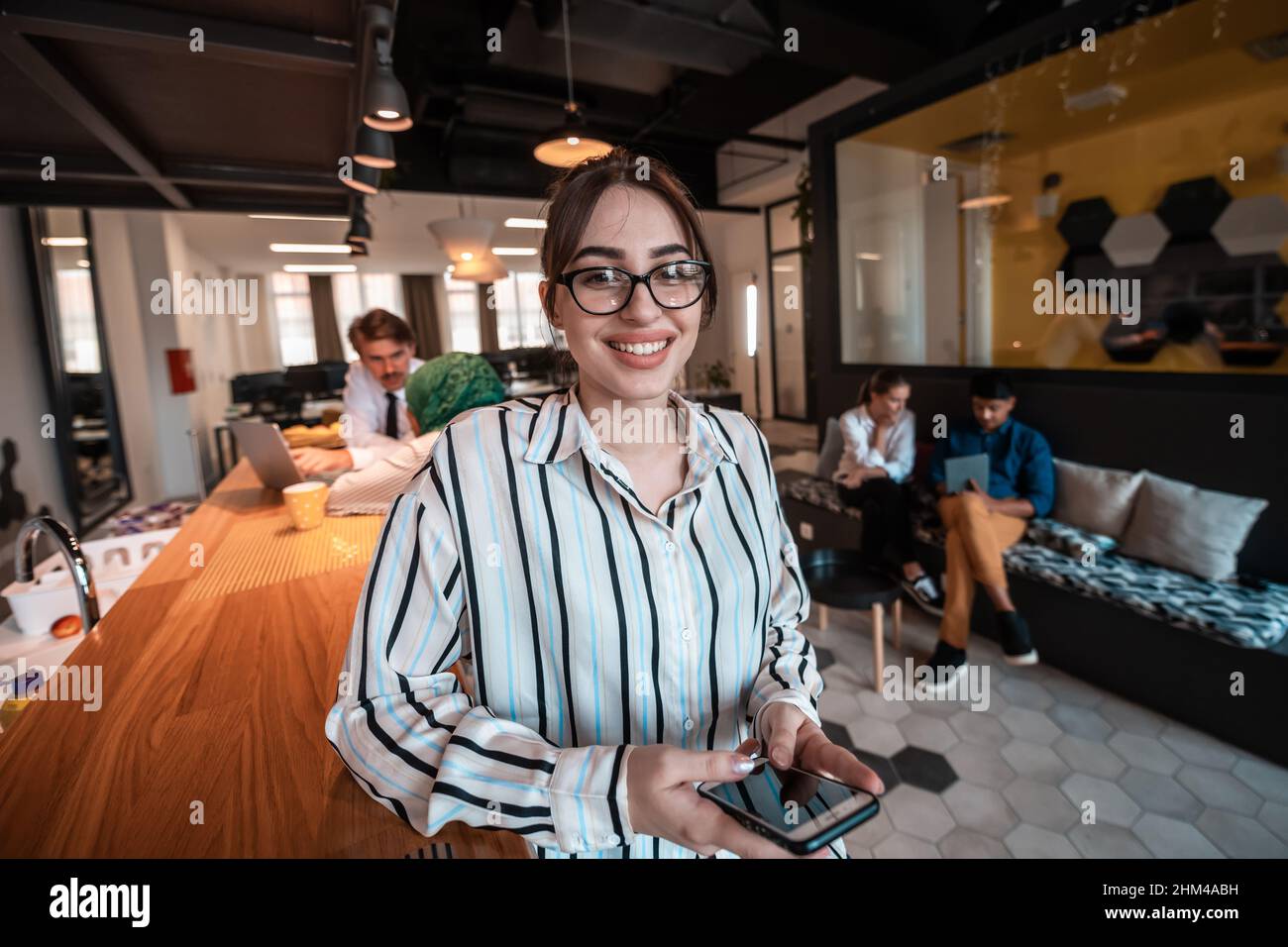 Businesswoman with glasses using mobile phone at modern startup open ...