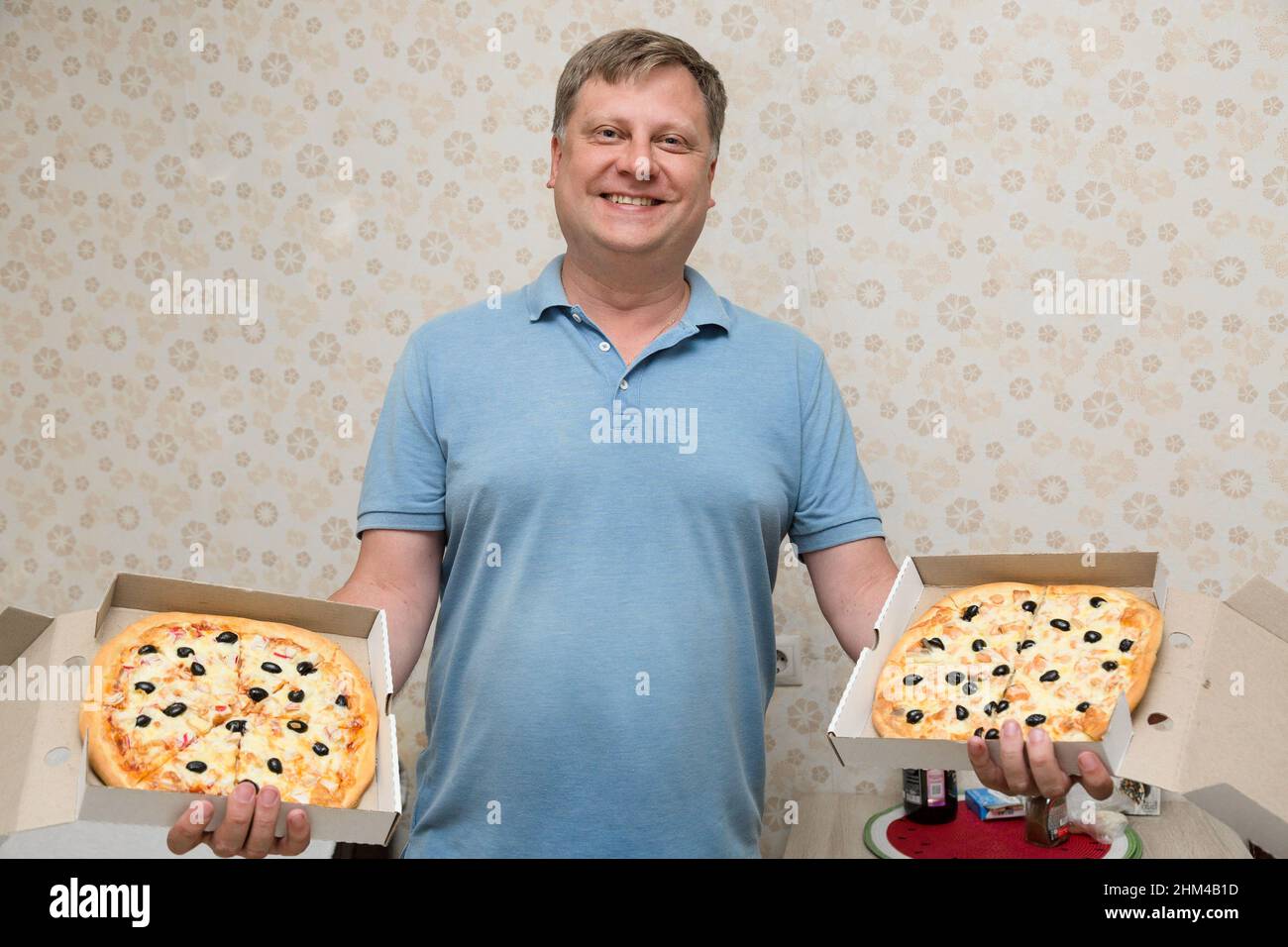 Adult tall man smiling broadly holding two pizza boxes Stock Photo - Alamy
