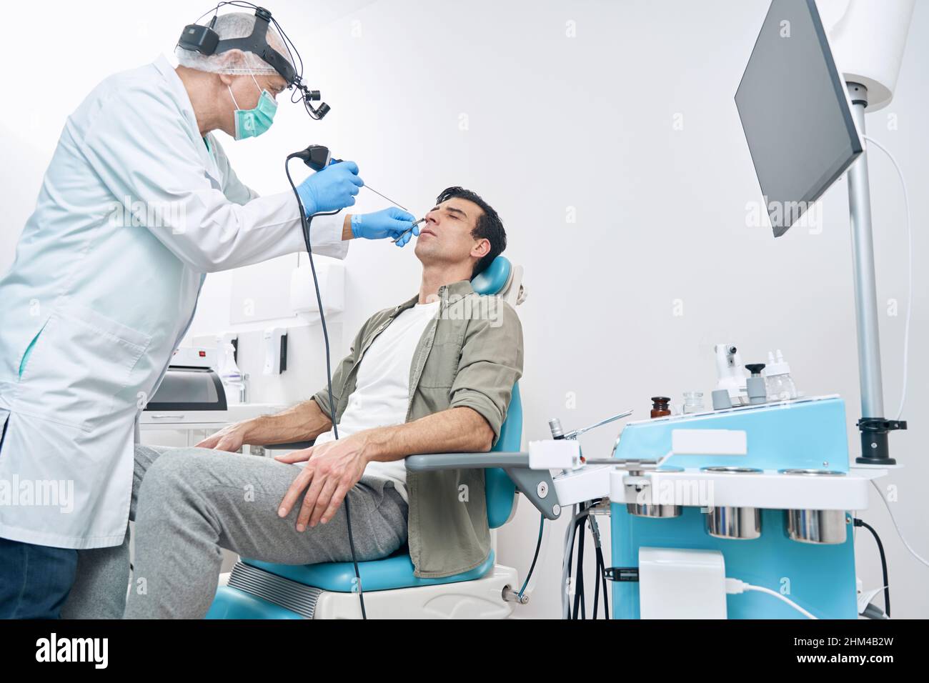 Doctor examining man with medical instrument at the hospital Stock ...