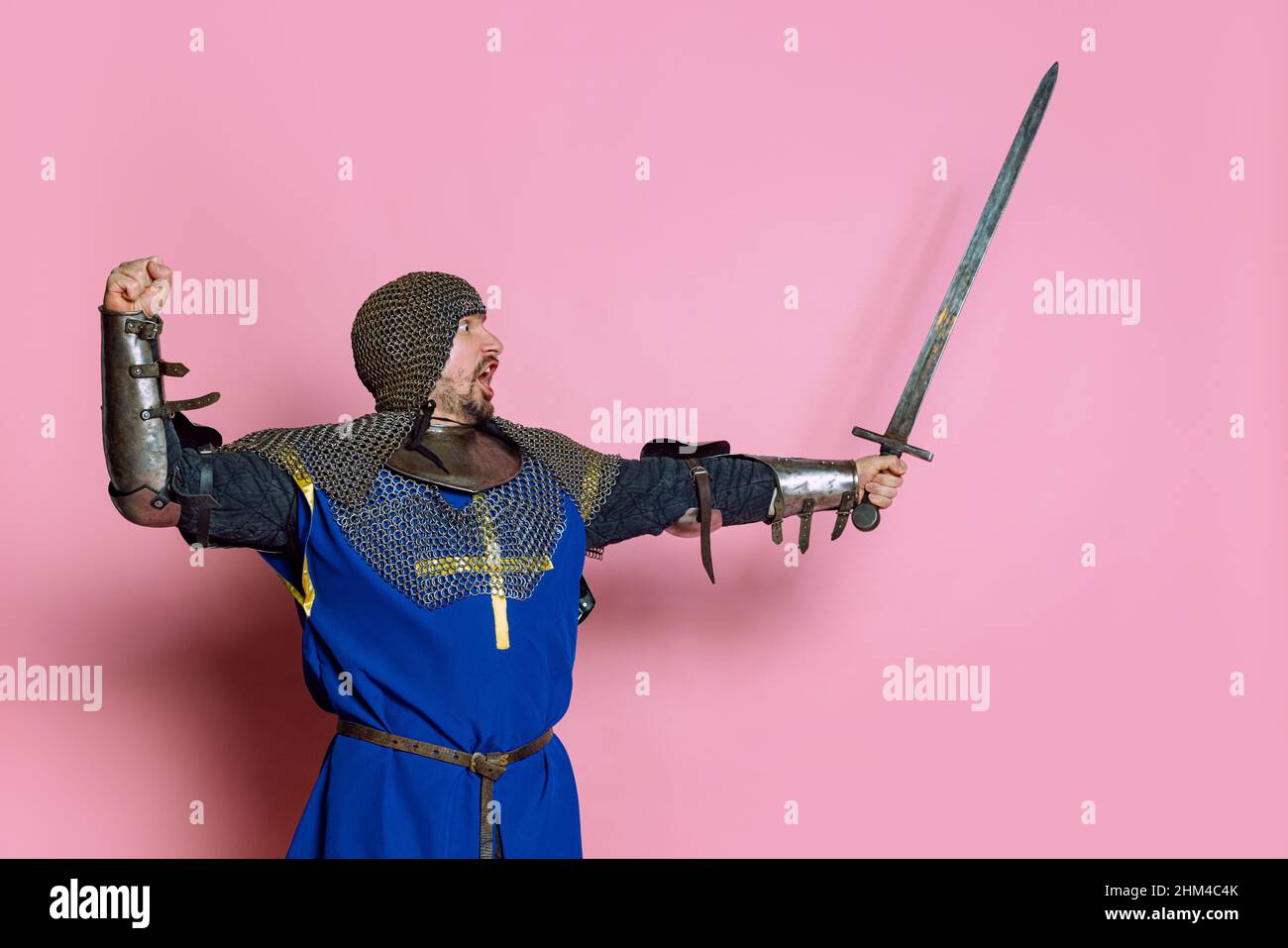 Portrait of brave man, medieval warrior or knight in armor rising sword ...