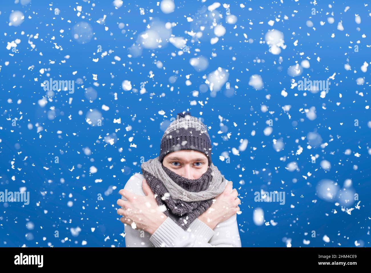 A frozen guy in a jacket and a scarf under the falling snow. Snow ...