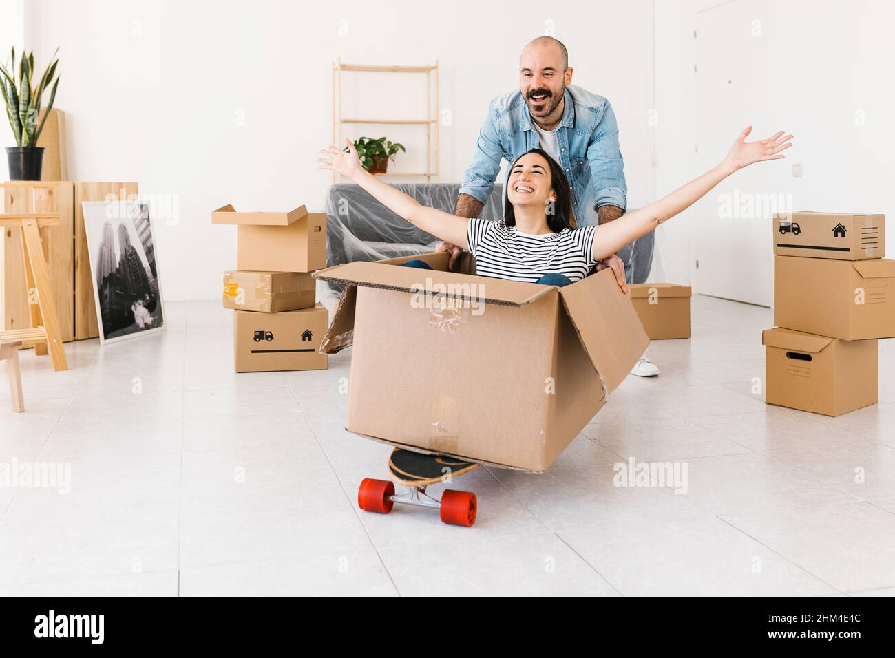 Happy couple having fun while unpacking on moving day in new apartment ...