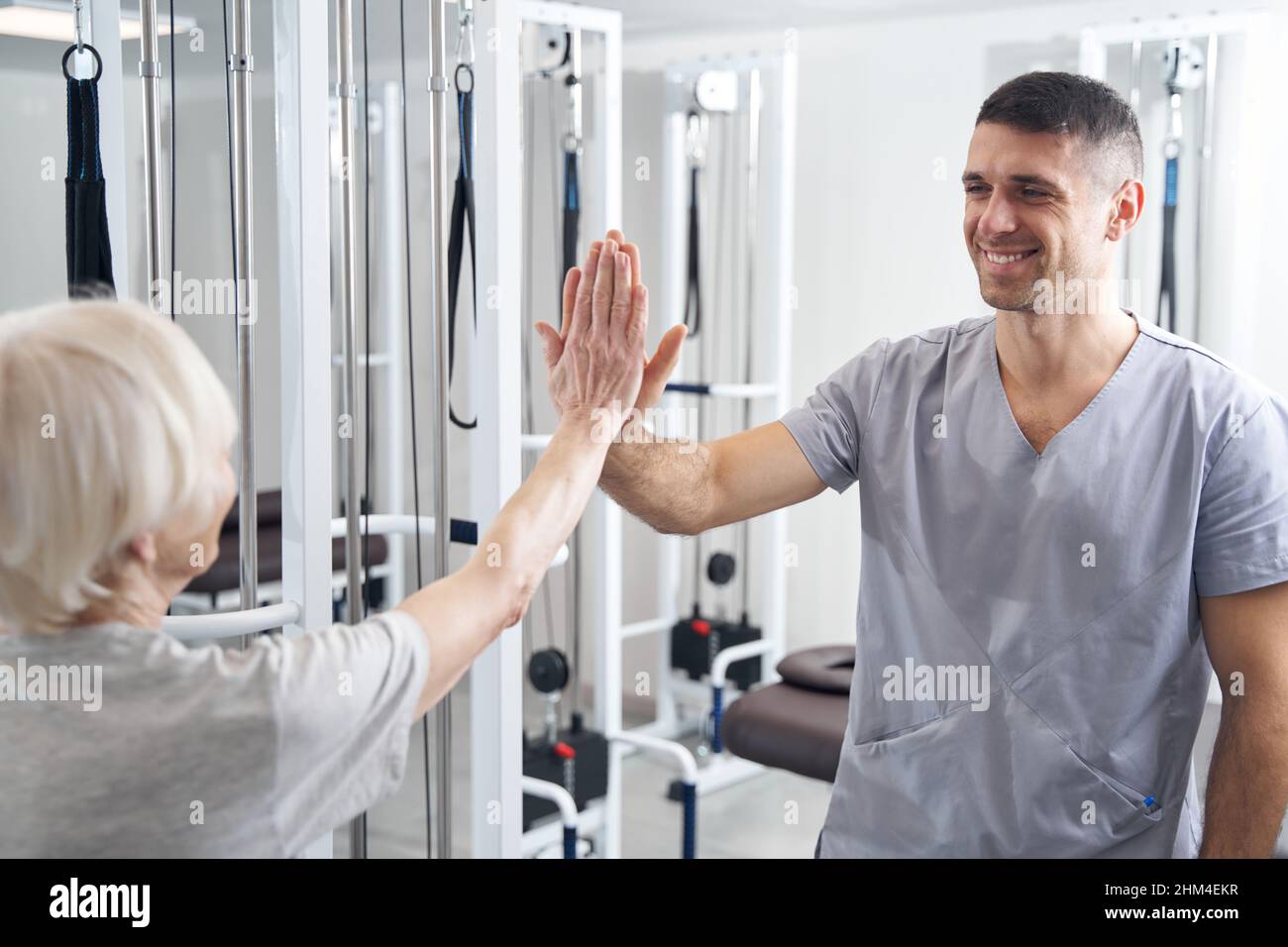 Pleased man medical professional giving high five to senior patient ...