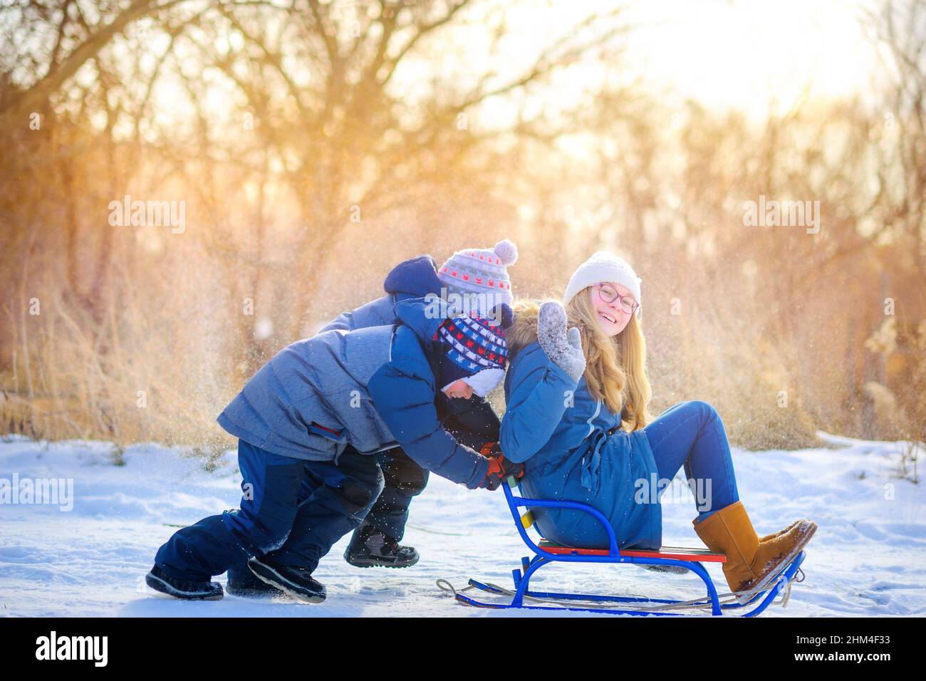 Happy children play in a snowy winter park. Sledding and having fun ...