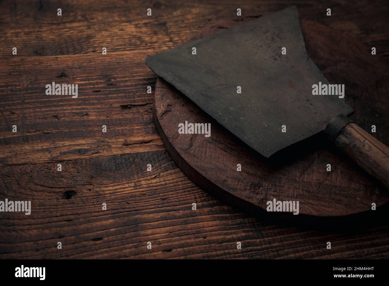 big ancient cleaver ready to be used again, on top of an old wooden ...