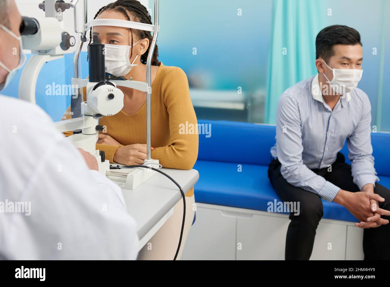 Serious female patient in medical mask getting her eyes examined in ...