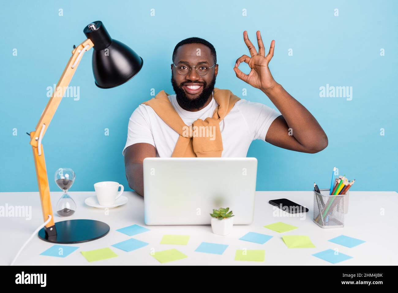 Photo of reliable guy sit table pc show okey symbol wear t-shirt jumper ...