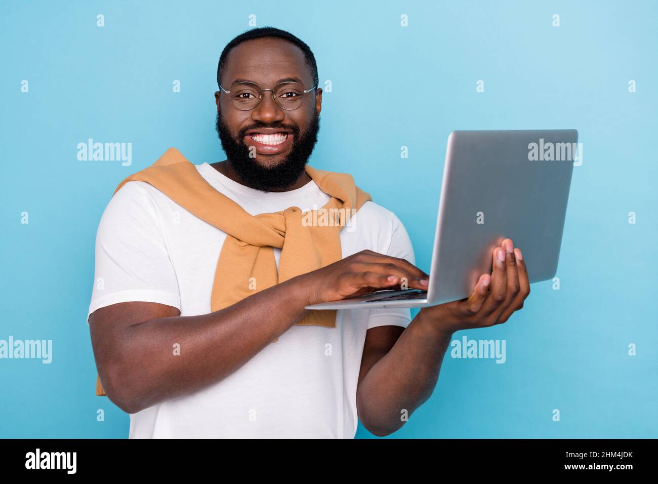 Photo of cheerful programmer guy hold netbook typing wear white t-shirt ...