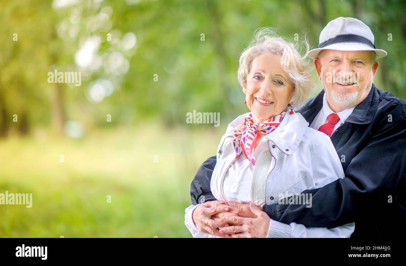 happy elderly couple hugging tightly while standing in a park at sunset ...